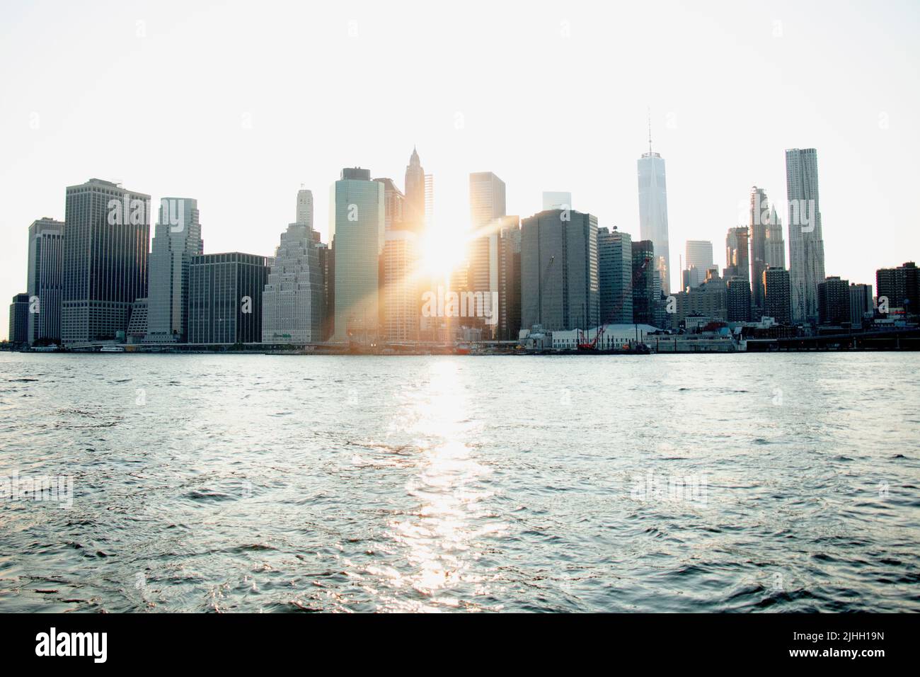 New York City seen from the sea with shining water and the sun in ...