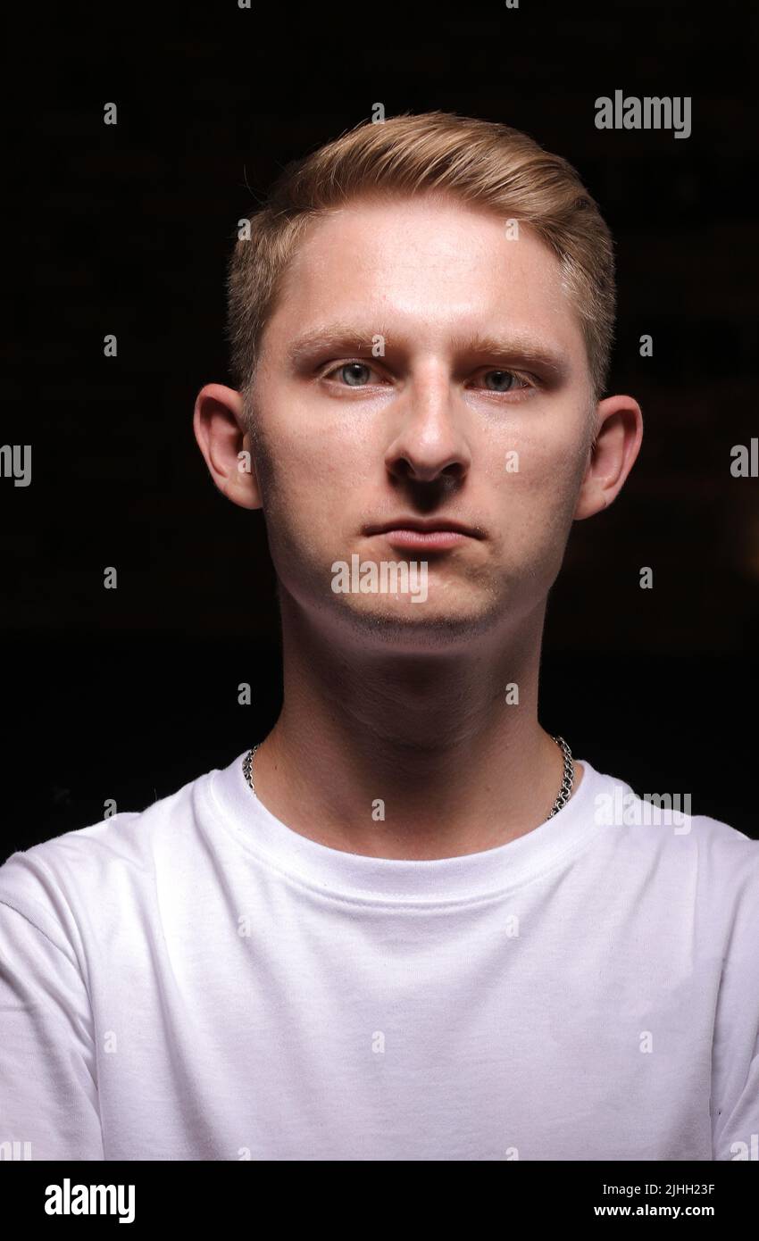 portrait of serious young man with folded and crossing hands standing ...