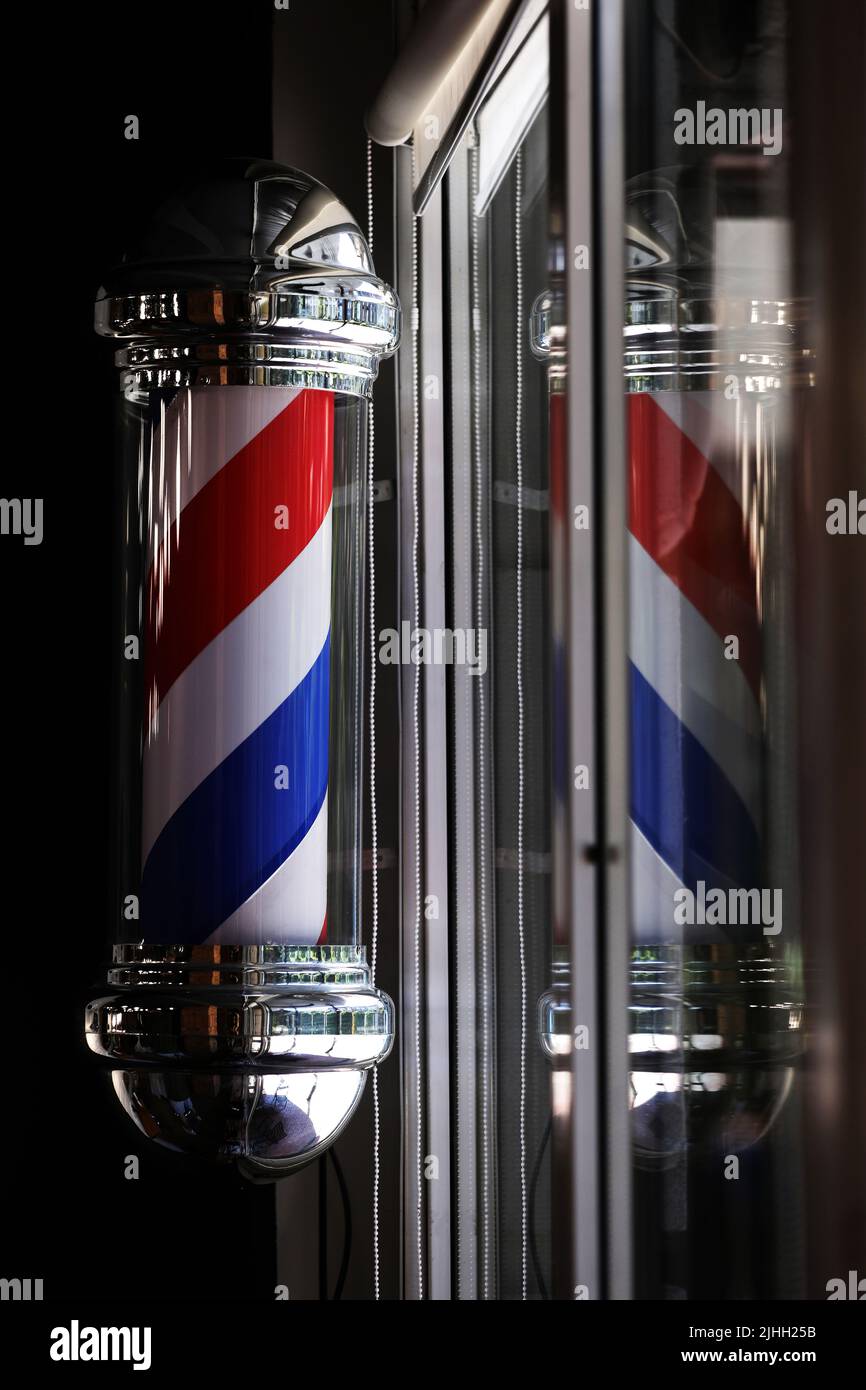 Barber pole spinning at night. International barbershop pole sign. A ...