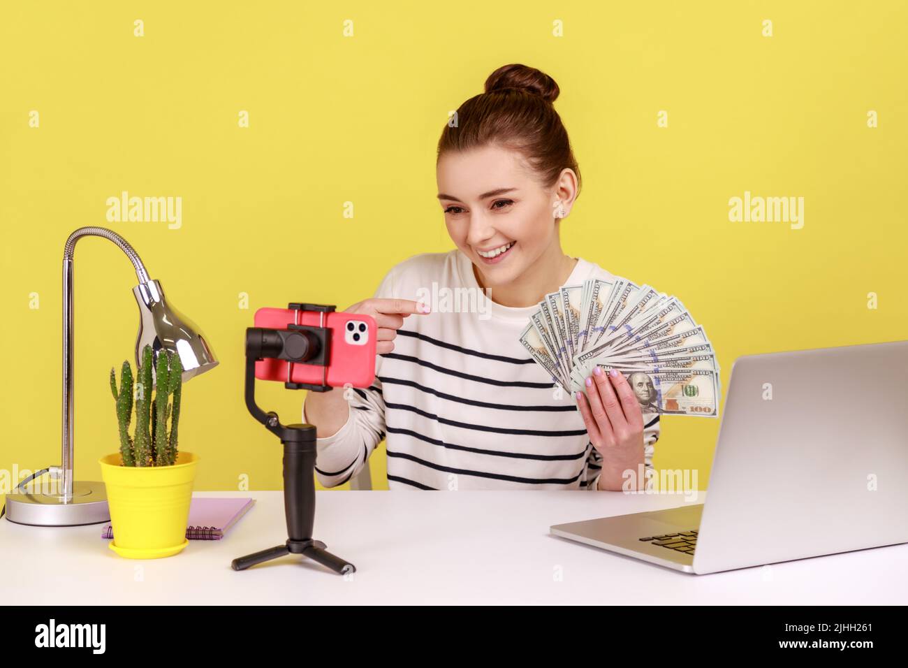 Woman pointing finger at dollar cash, recording video to her followers ...