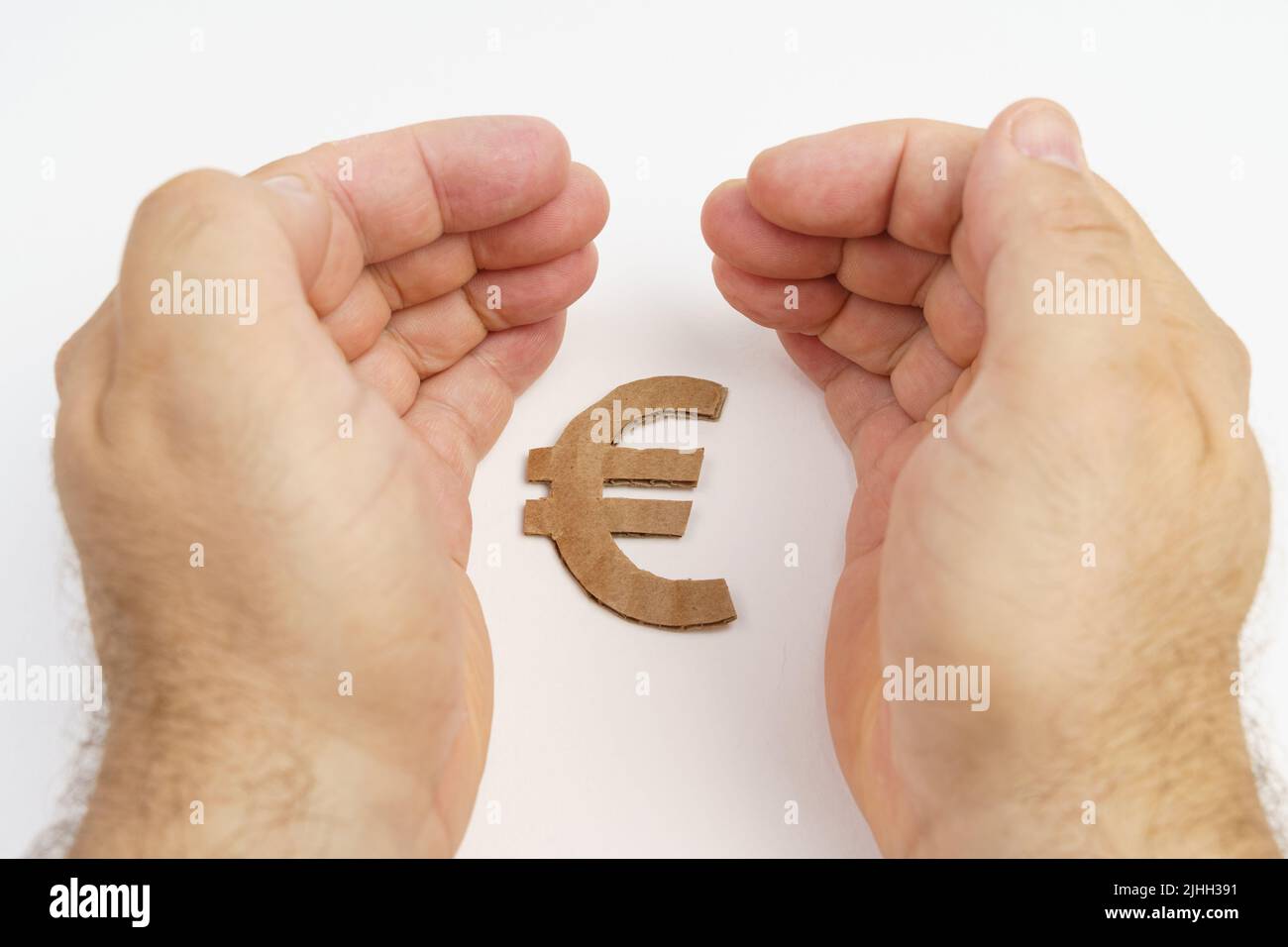 On a white background, the symbol of the euro, human hands protect it ...