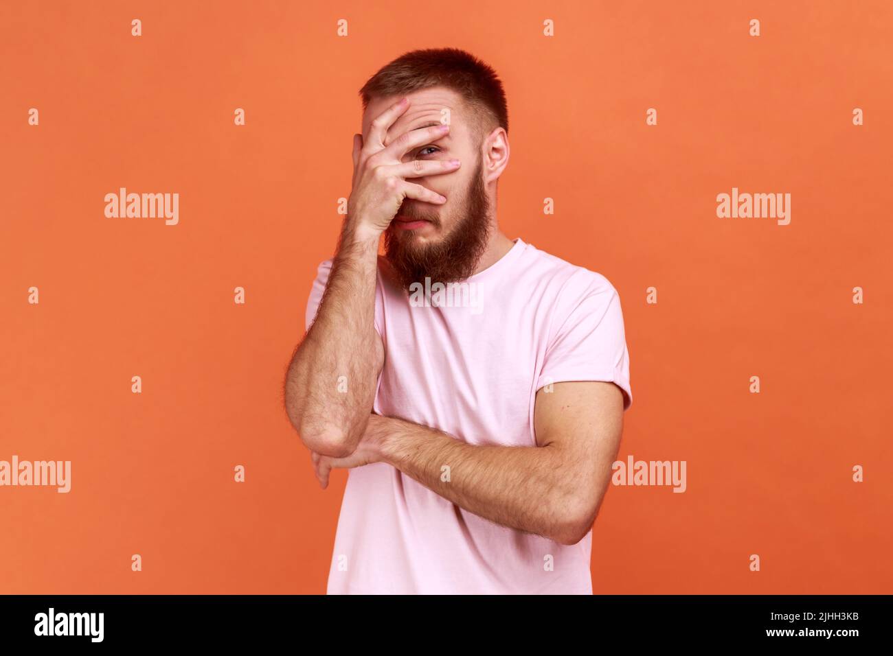 Portrait of curious bearded man spying through hole in fingers closing ...