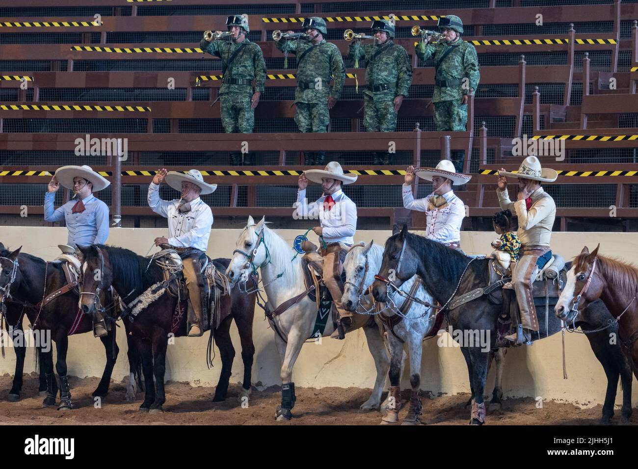 Mexican soldiers play the national anthem as rodeo riders stand at ...