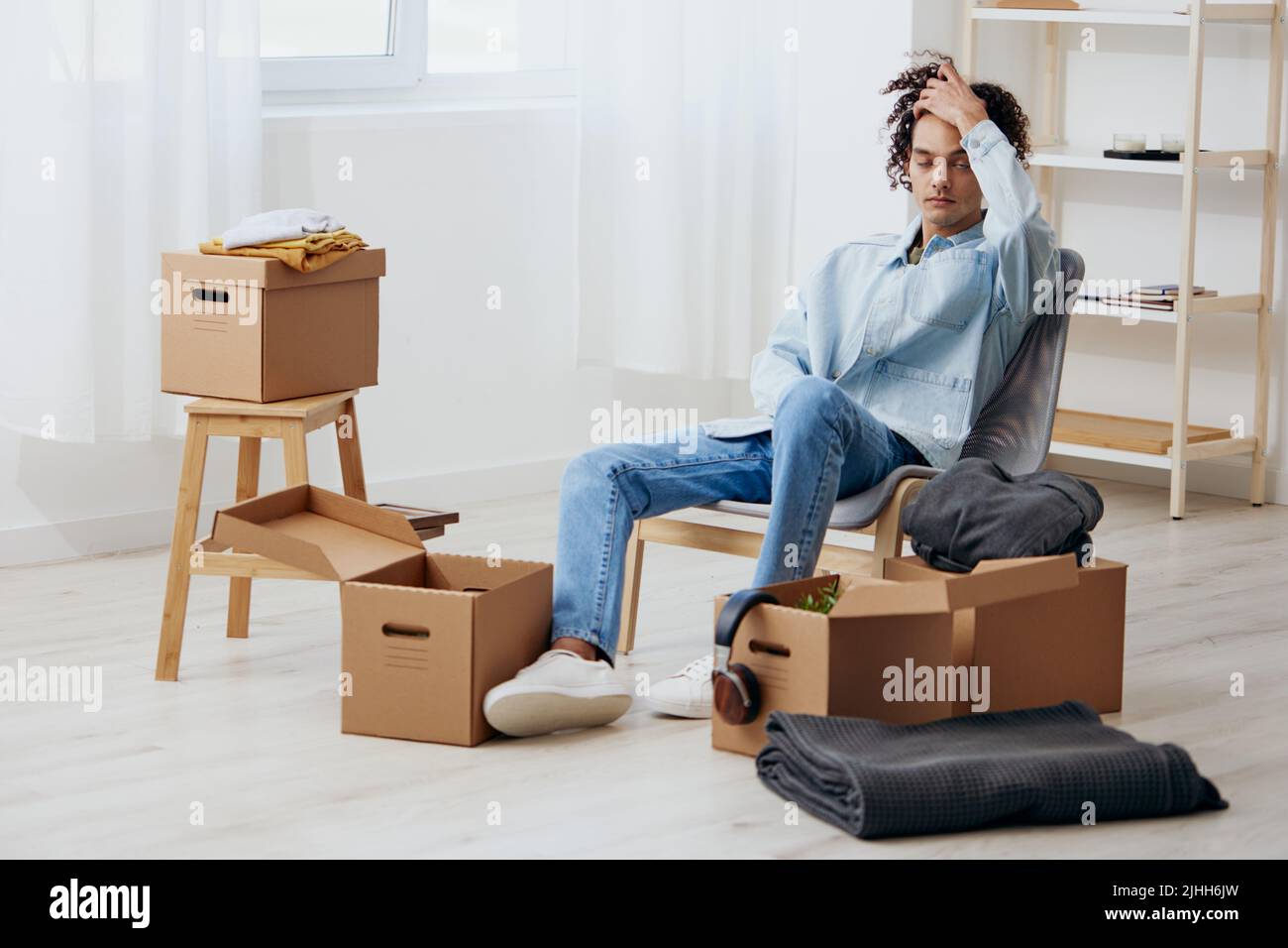 guy with curly hair unpacking things from boxes in the room sorting ...