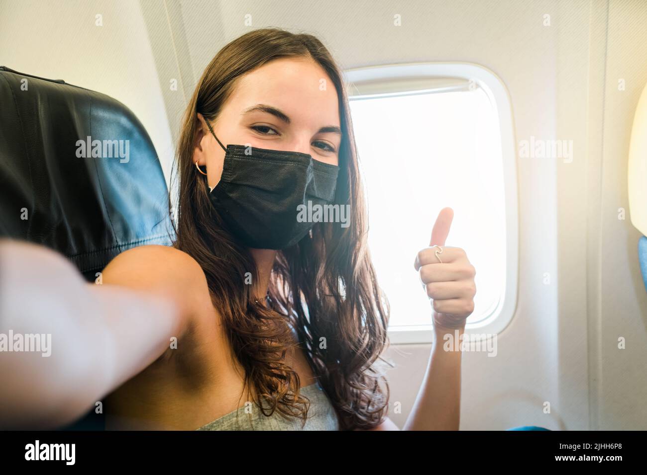 girl wearing face mask taking selfie with smartphone while sitting on ...