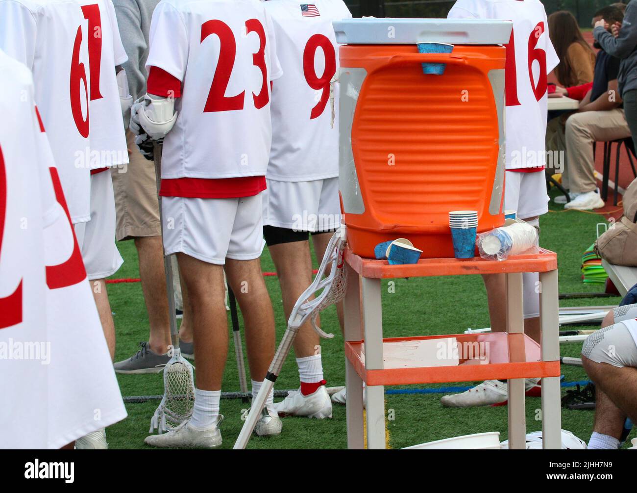 Orange water cooler on a stand by the athletes on the bench of a ...