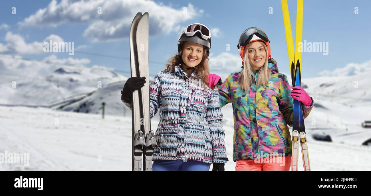 Two young women in ski uniforms posing on a snowy mountain Stock Photo ...