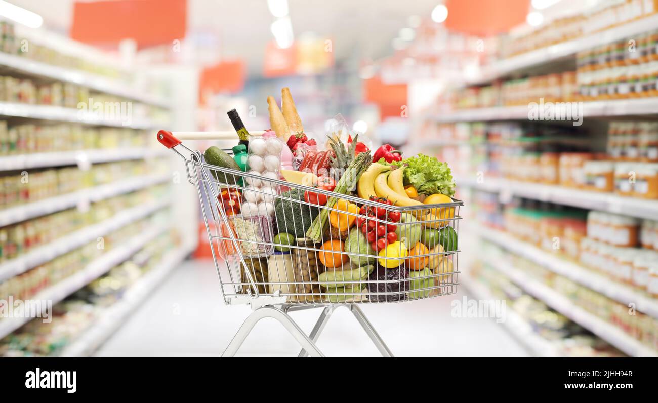 Full shopping cart with groceries inside a supermarket Stock Photo - Alamy
