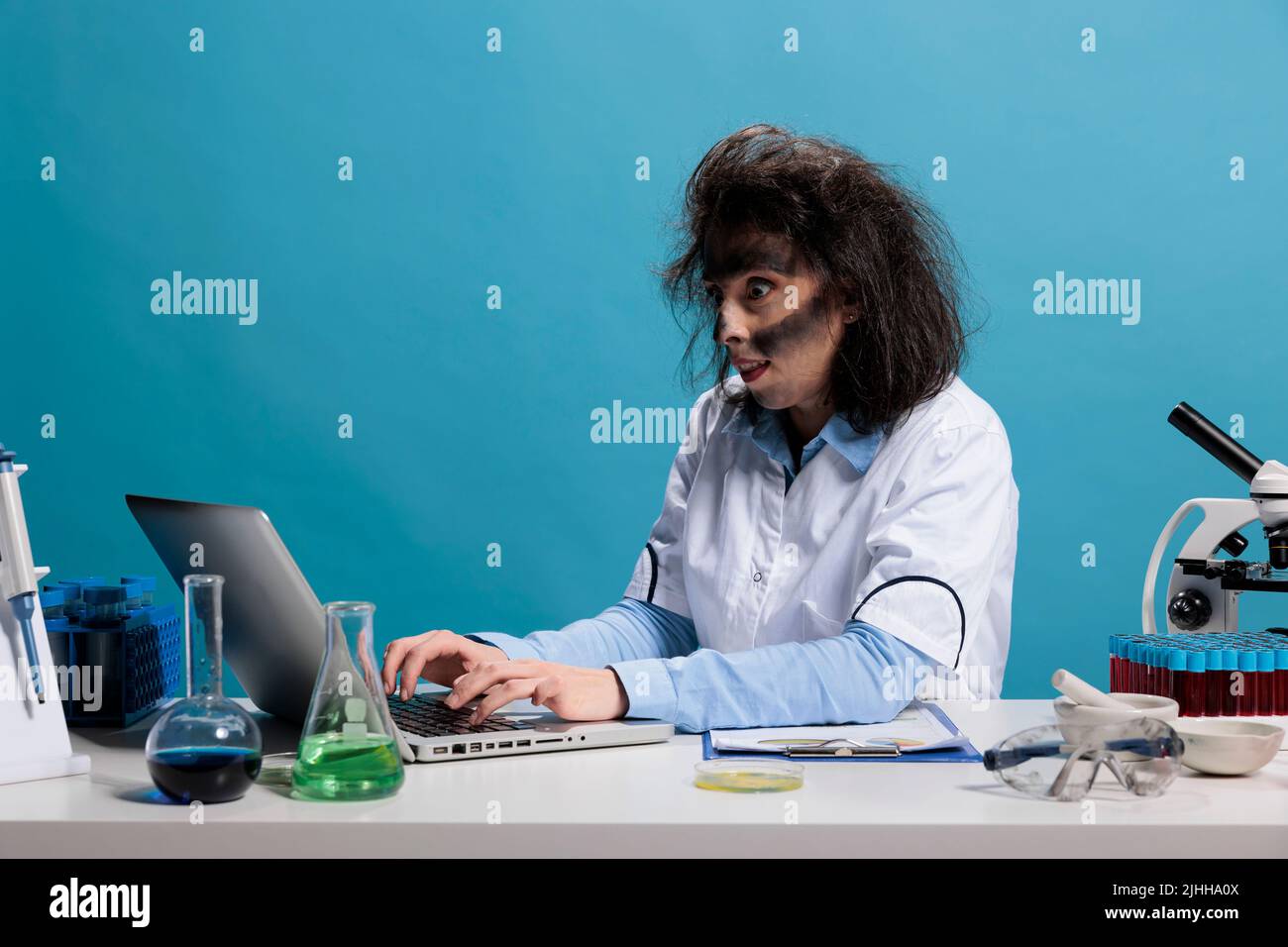 Maniac goofy scientist with wacky look using computer to analyze ...