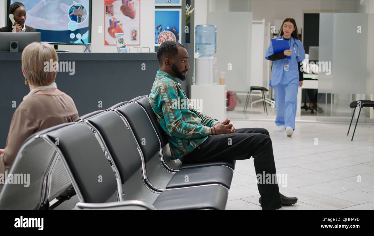 Male patient waiting in hospital reception lobby to attend medical ...