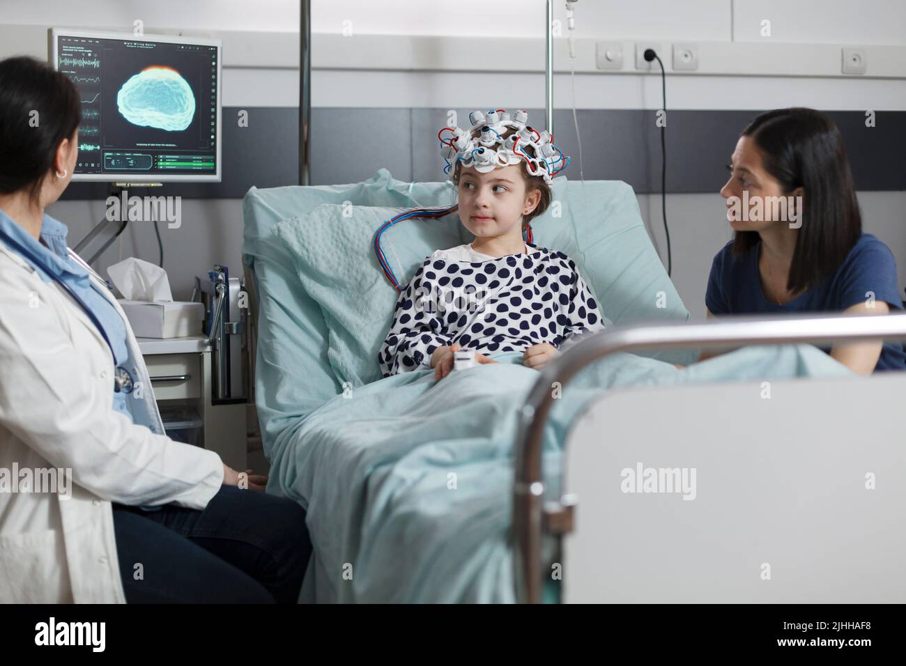 Hospitalized sick girl wearing EEG headset resting in patient bed while ...