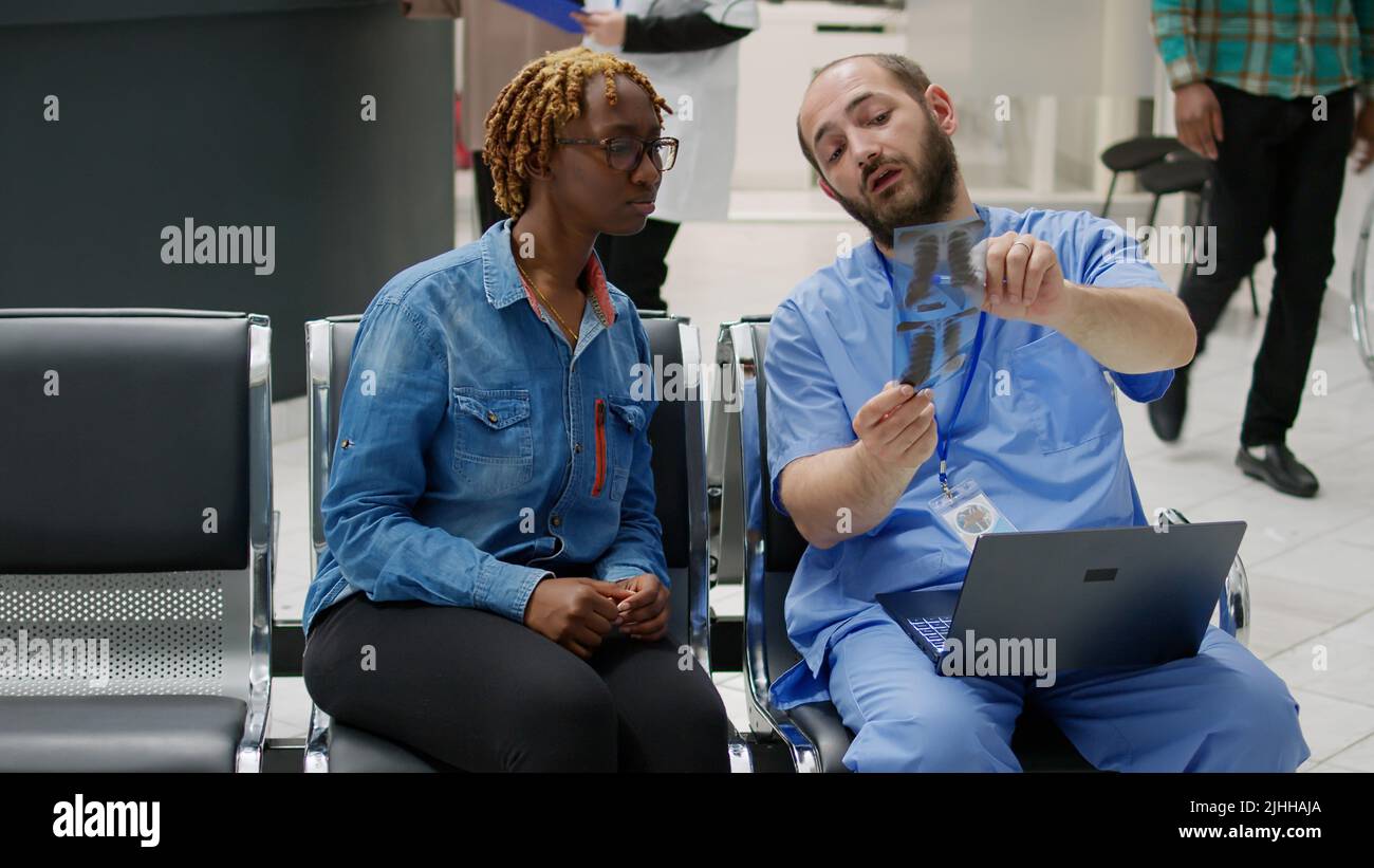 Male nurse showing bones radiography results to patient sitting in ...