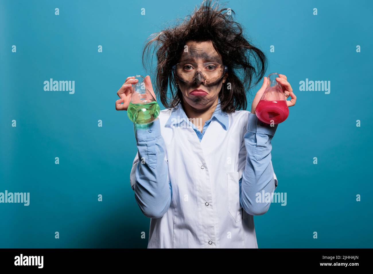 Sad lunatic chemist holding glass flasks filled with chemical compounds ...