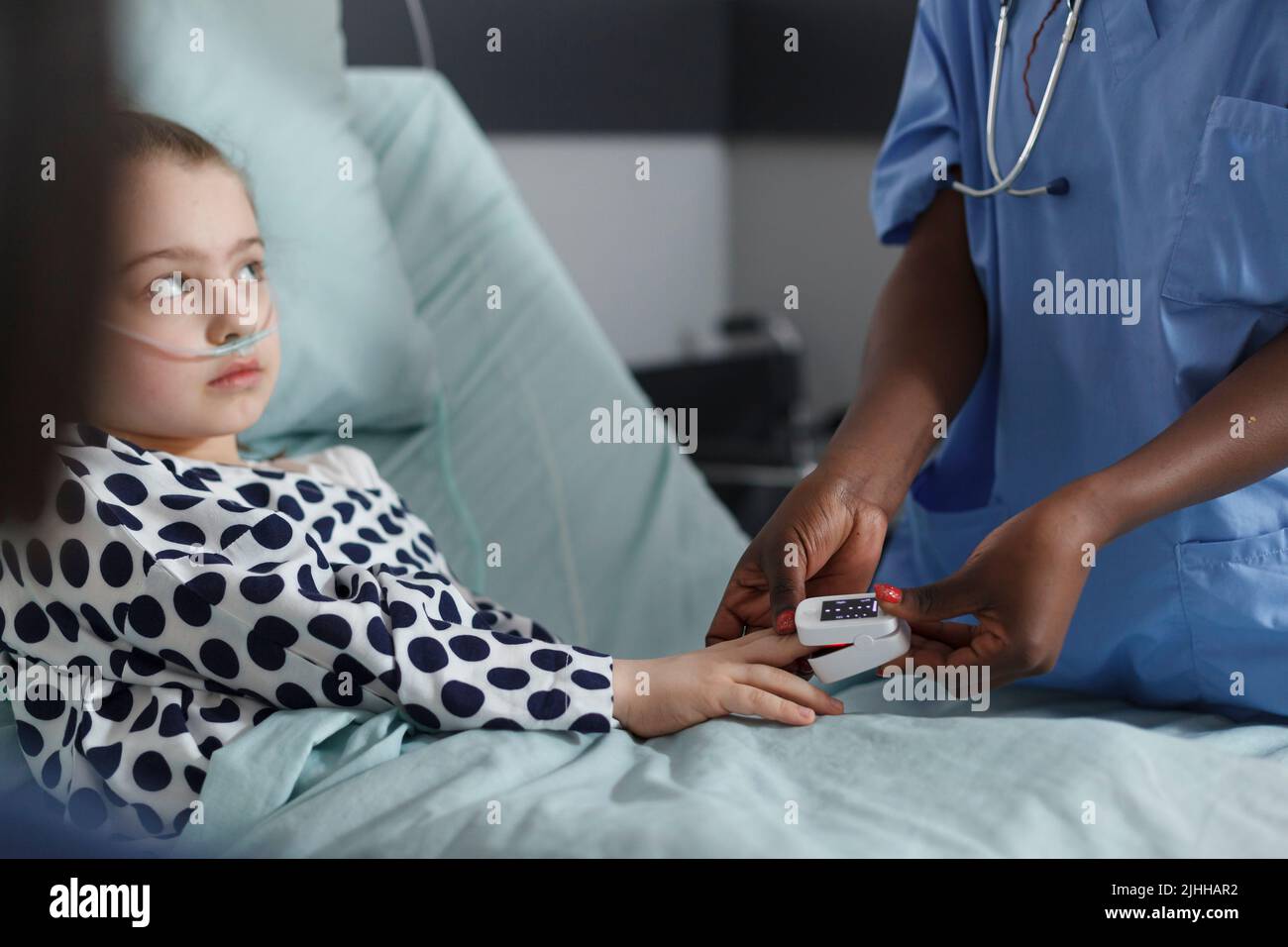 Nurse measuring oxygen levels of hospitalized sick little girl resting ...
