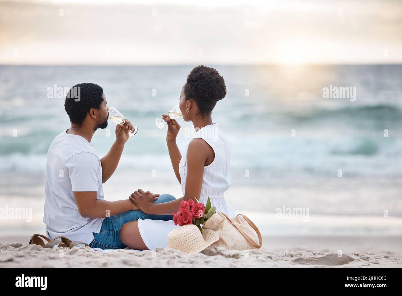 Young content african american couple drinking champagne at the sea ...