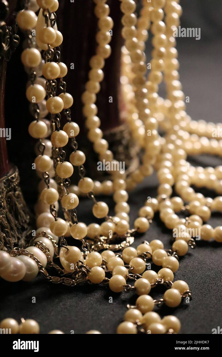 A pile of various pearl necklaces up close and on a neutral backdrop ...