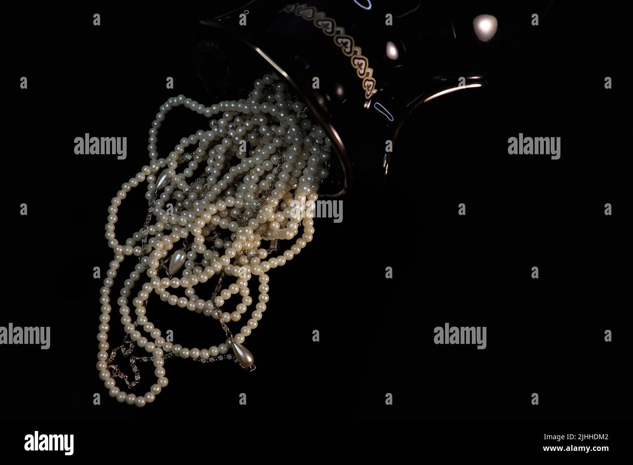 A pile of various pearl necklaces up close and on a neutral backdrop ...