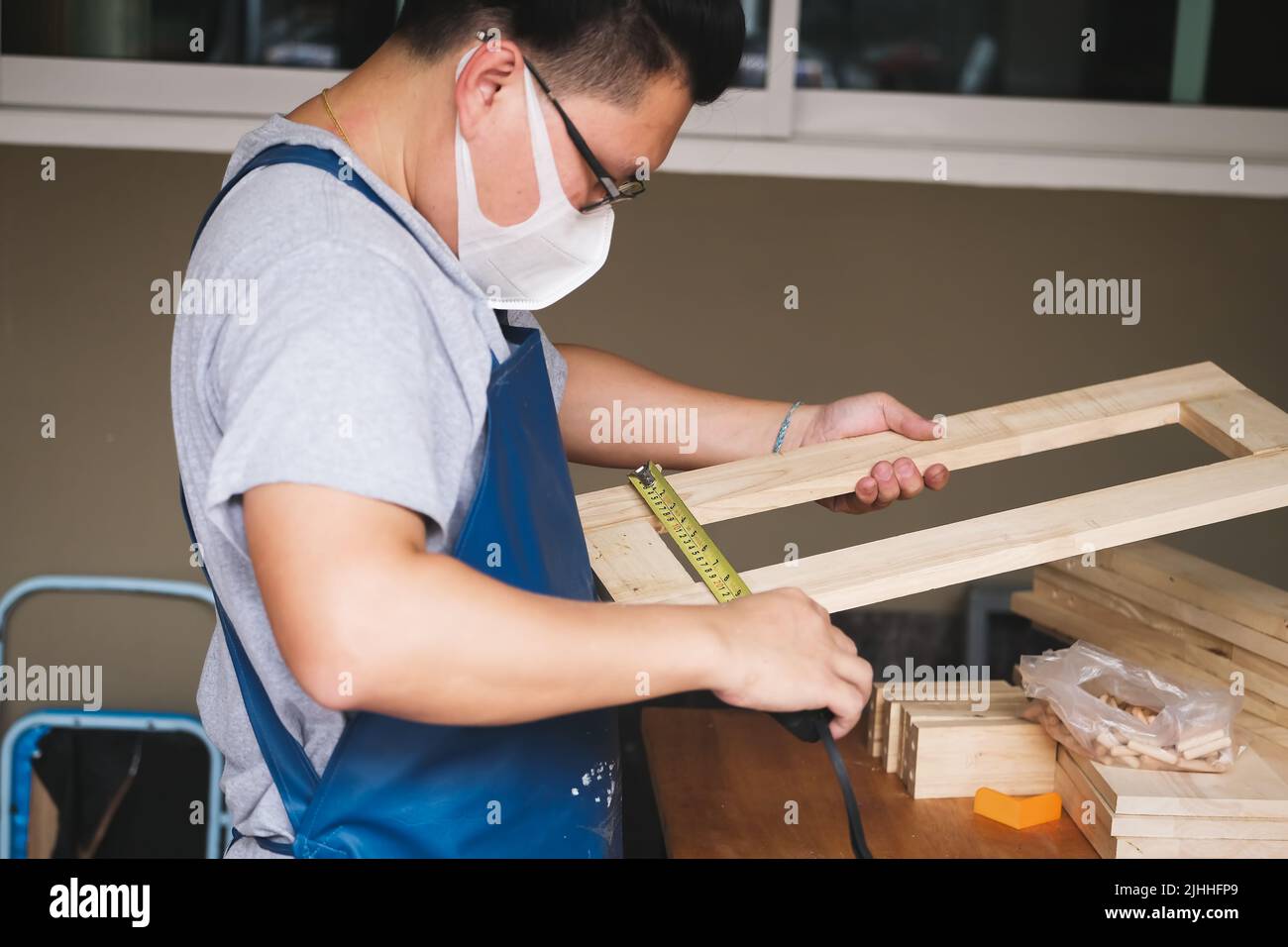 A carpenter measures the planks to assemble the parts and build a ...