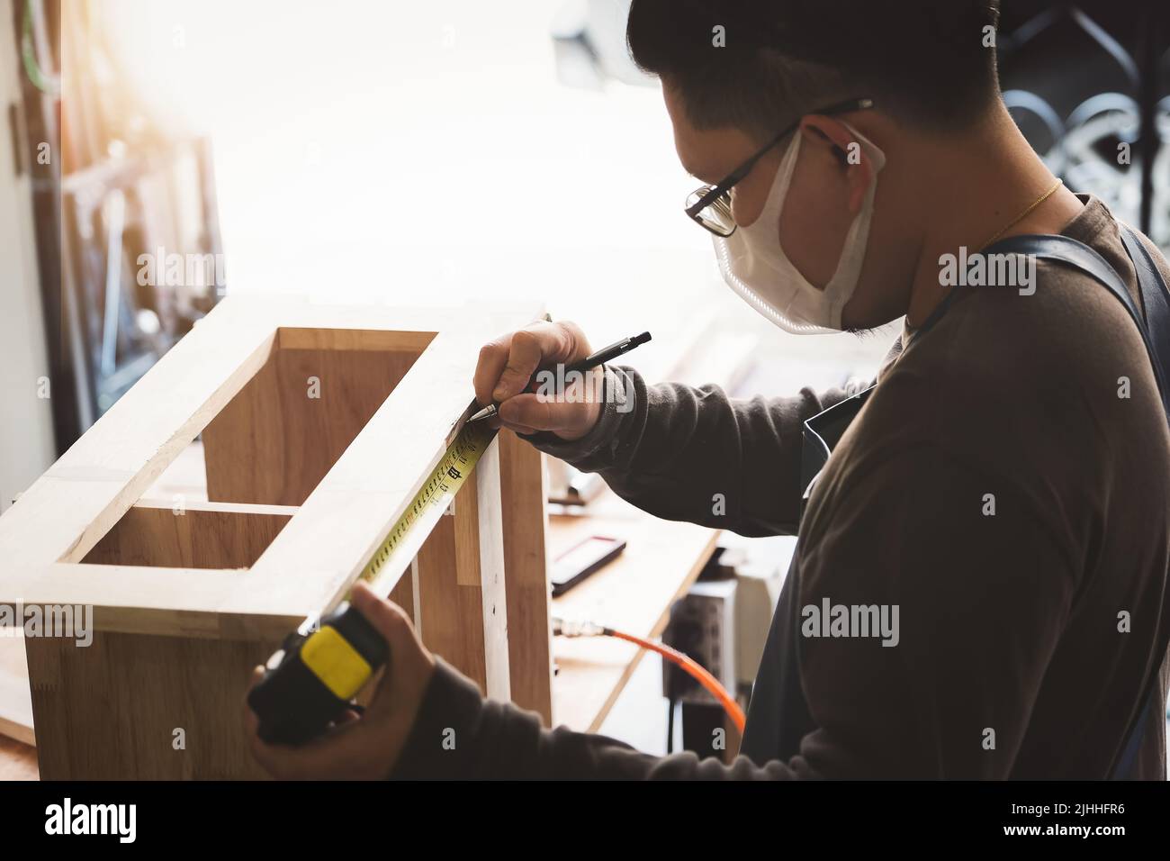 A carpenter measures the planks to assemble the parts, and build a ...