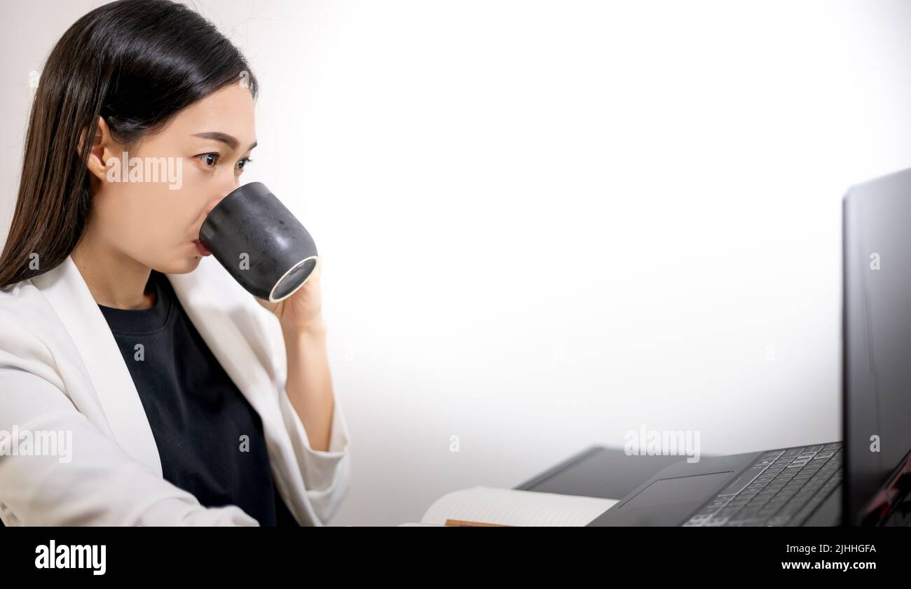 Female drinking water with a black glass while working with the laptop ...