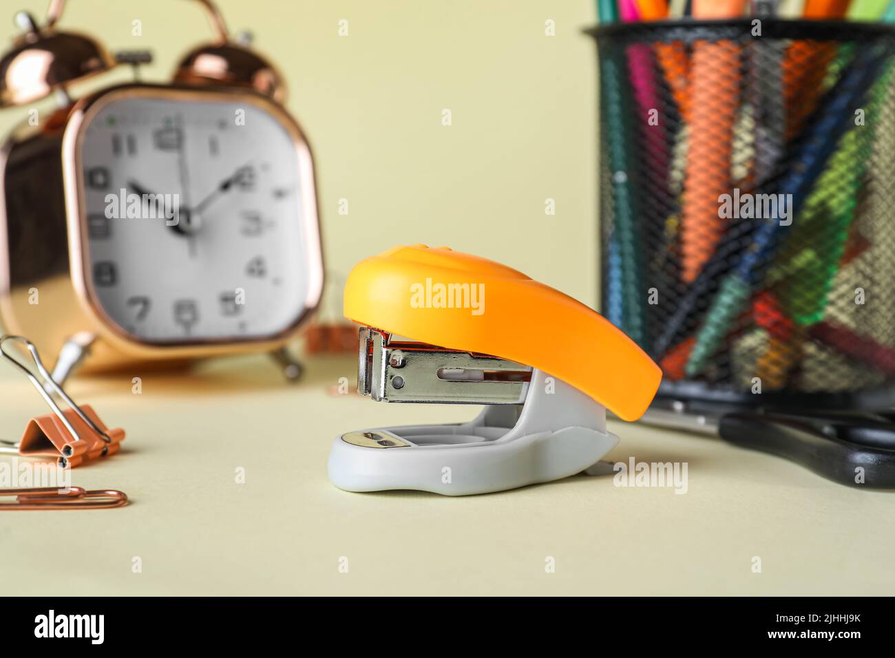 Stapler with stationery supplies and alarm clock on beige background ...