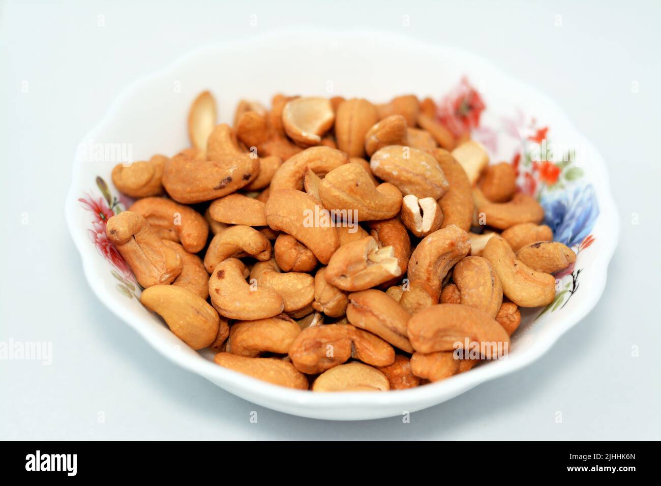 a plate with a pile of peeled roasted salted cashew nuts seeds isolated ...