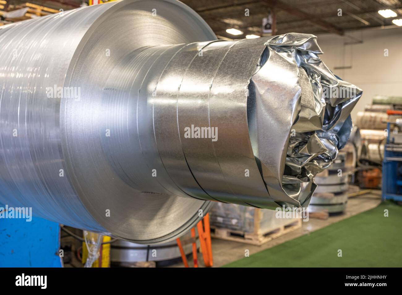 Damaged metal roll of coil on decoiling machine Stock Photo - Alamy