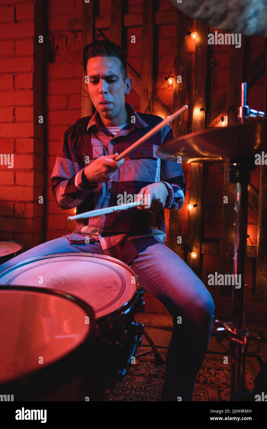Serious male player with wooden drumstick playing drums on stage during ...