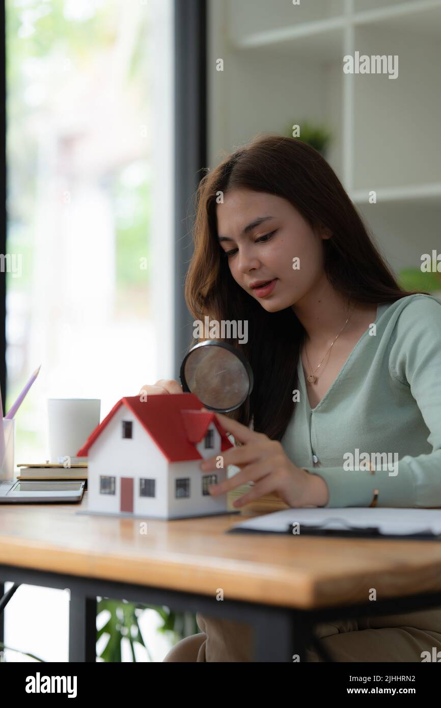 A woman holding magnifying glass and checking house model .Real Estate ...