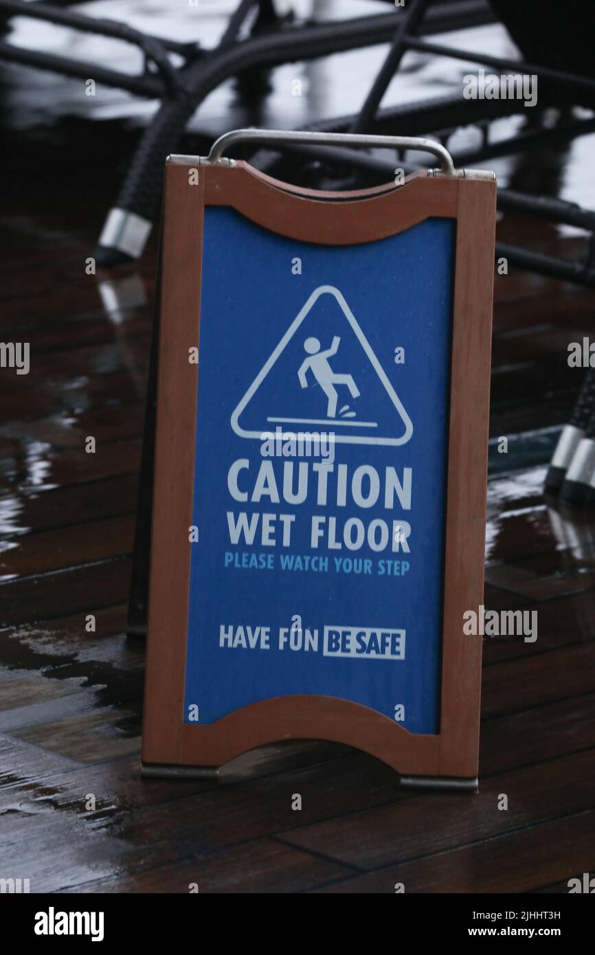 Wet floor caution sign on walkway near the building after raining ...