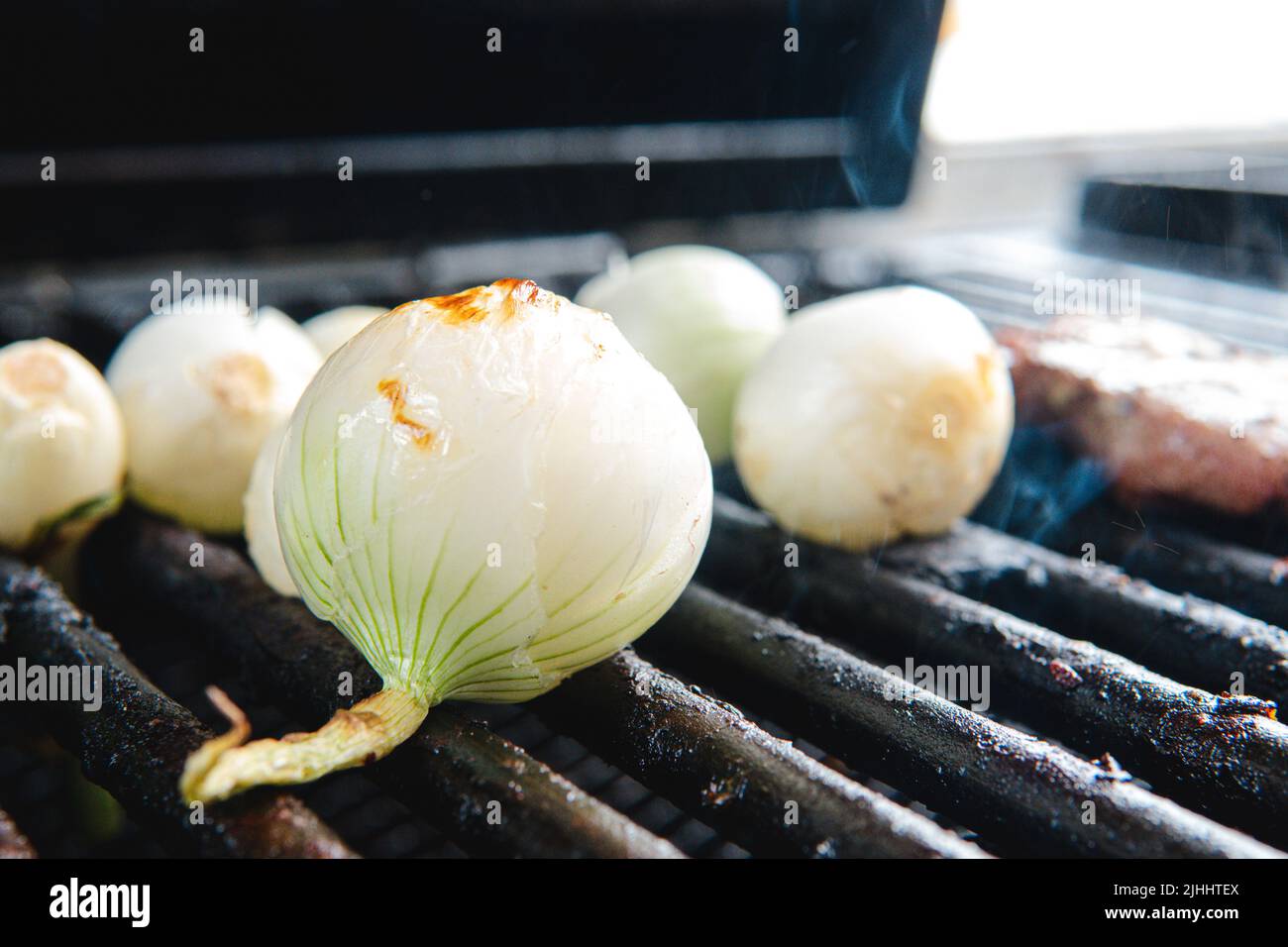 Close shot of onions on a spit. Grilling onions in a butcher shop. Meat ...