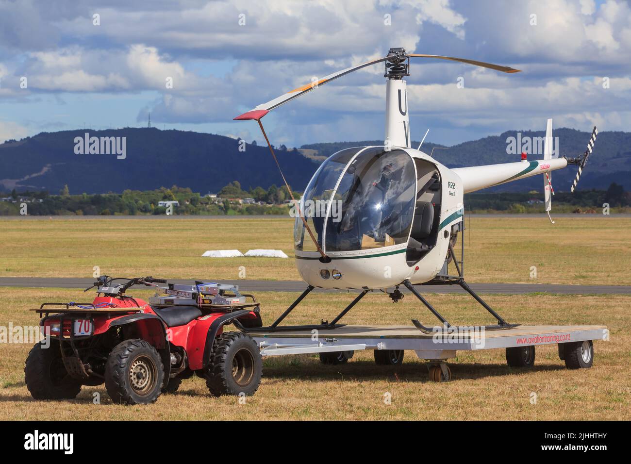 A Robinson R22 light utility helicopter on a trailer towed by a quad ...