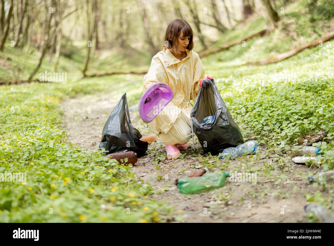Woman collecting scattered plastic garbage in the woods Stock Photo - Alamy