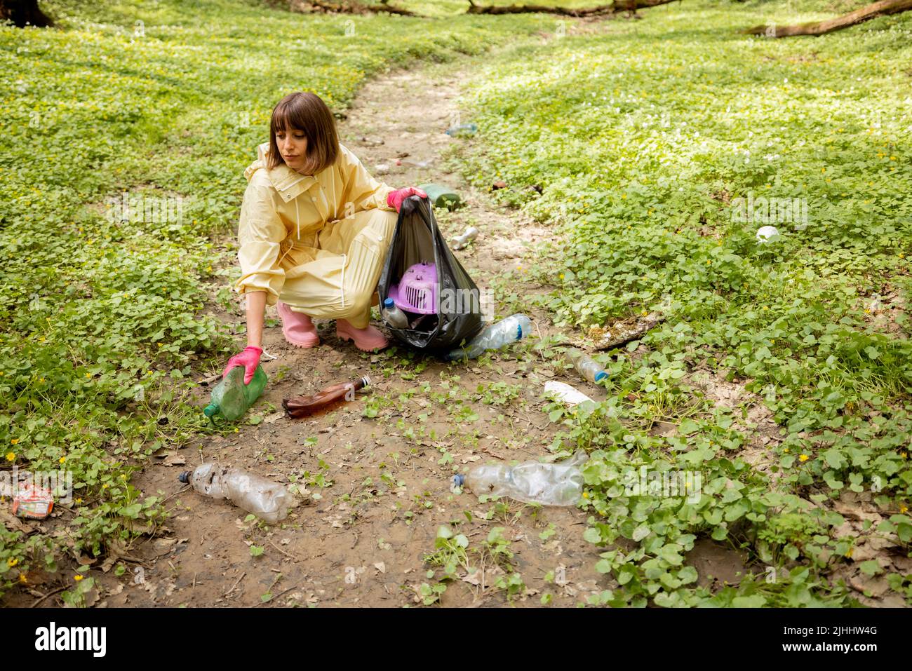 Woman collecting scattered plastic garbage in the woods Stock Photo - Alamy