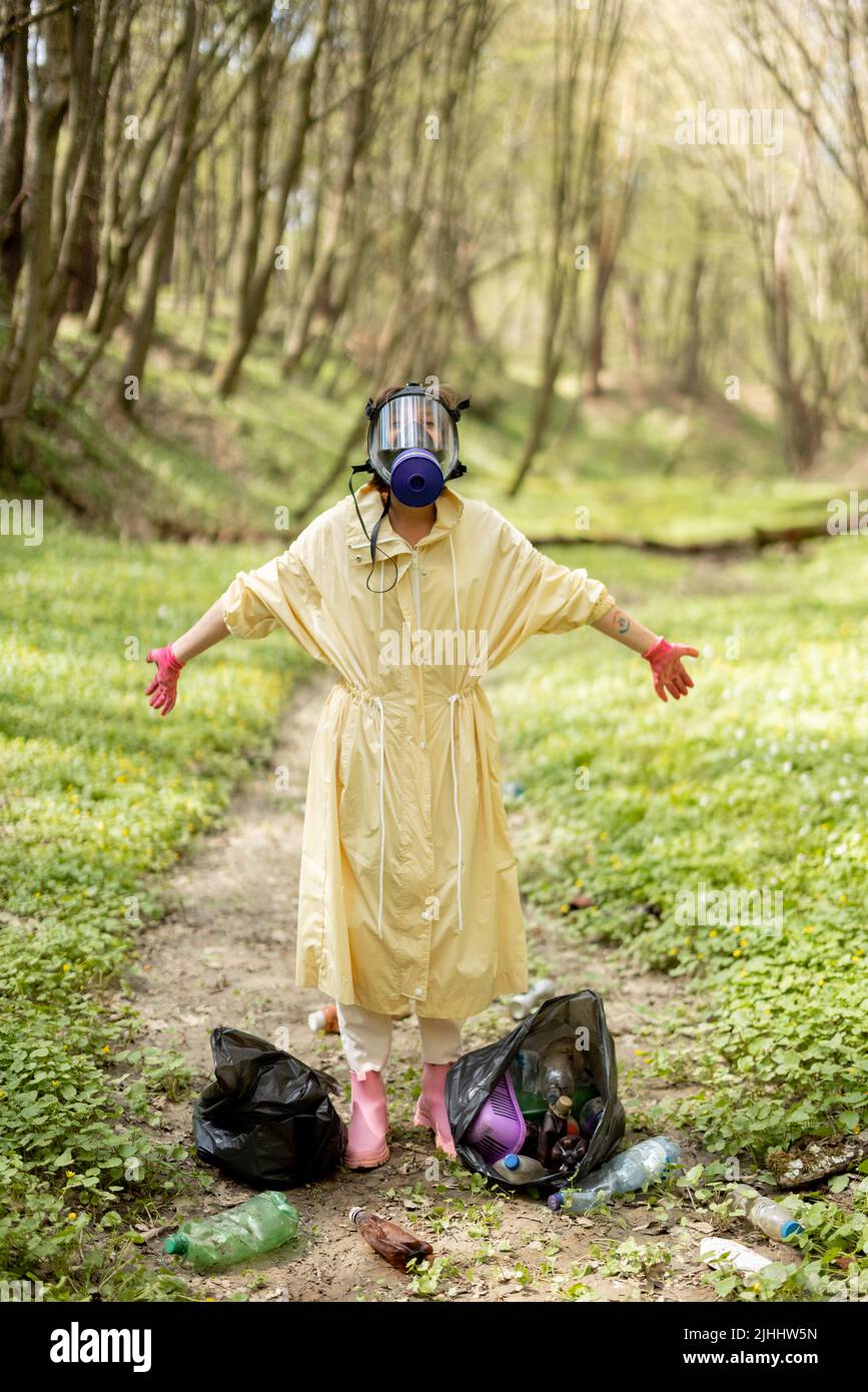 Woman in gas mask and protective clothes collecting scattered plastic ...