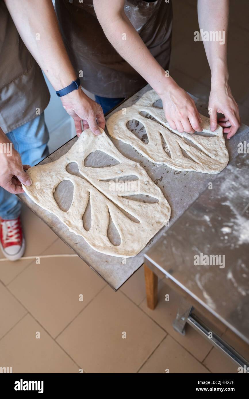 Bakers shape and cut traditional French Fougasse bread. Vertical photo ...