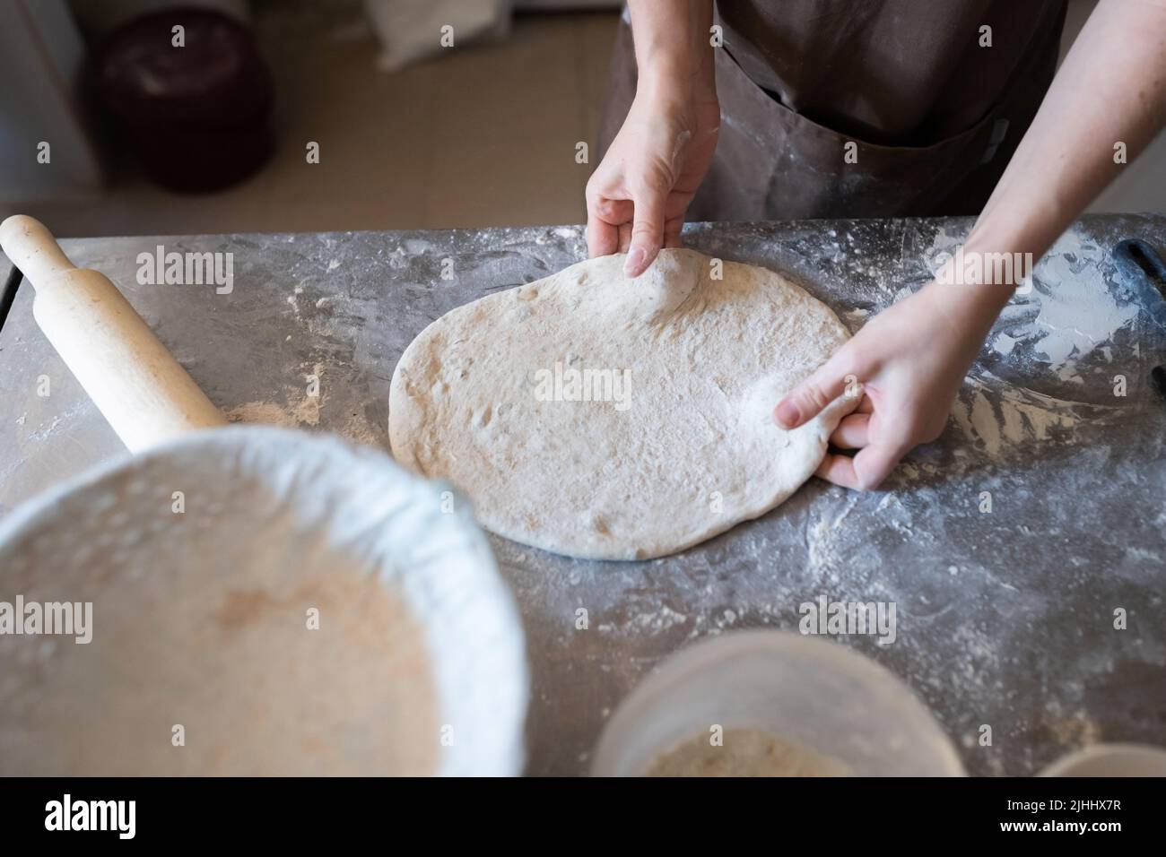 A baker shapes and cuts traditional French Fougasse bread. Front view ...