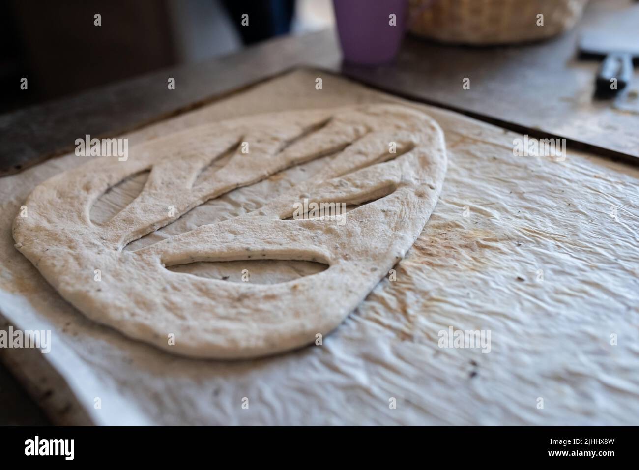 A baker shapes and cuts traditional French Fougasse bread. Front view ...
