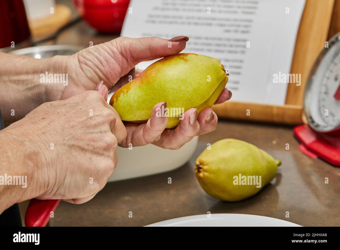 Chef cuts the pears into slices for chocolate cake with pear and nuts ...