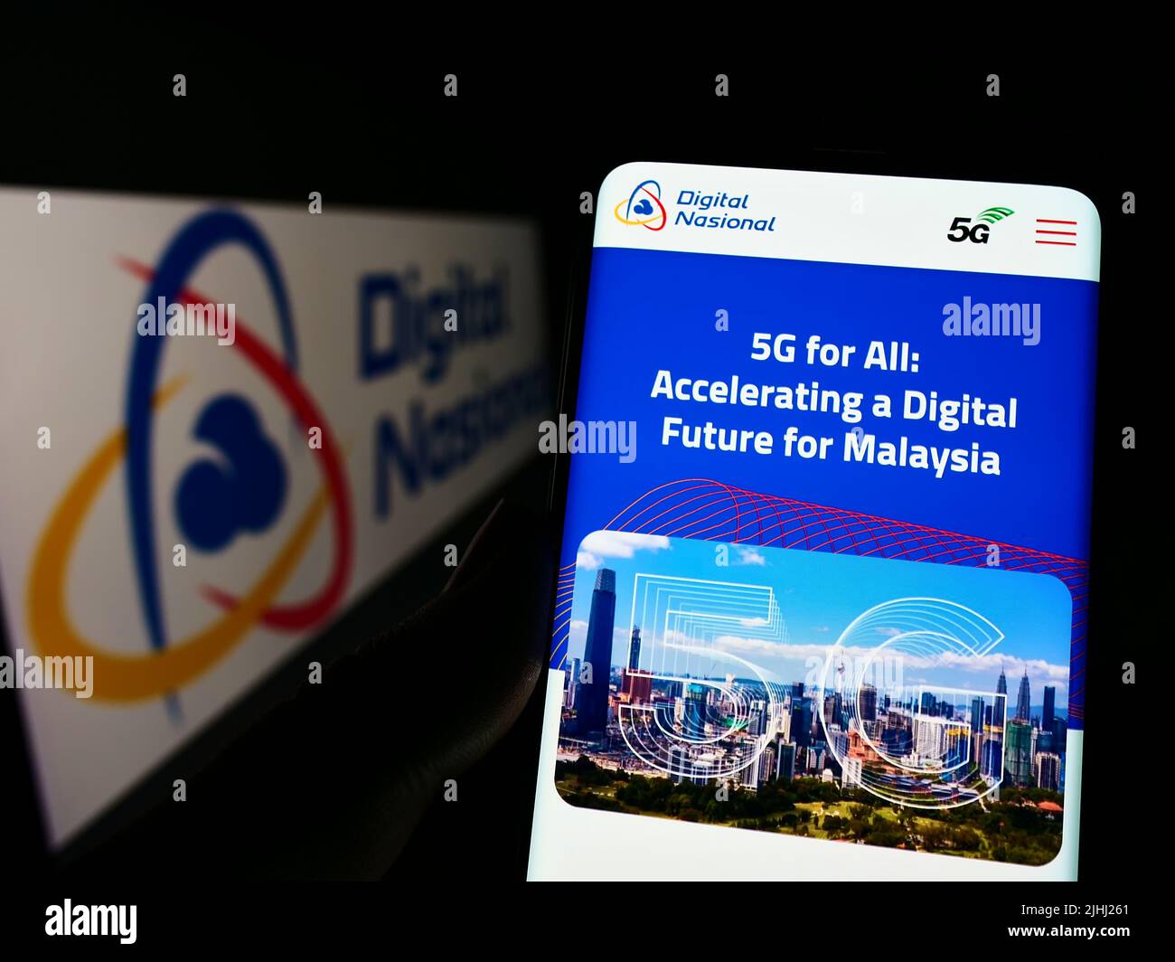 Person holding cellphone with webpage of Malaysian company Digital ...