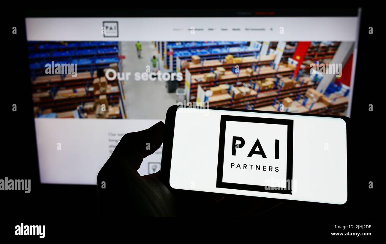 Person holding mobile phone with logo of French investment company PAI ...