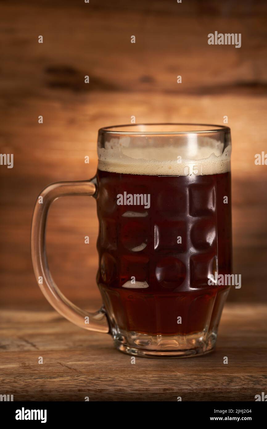 A pint of dark red beer on a rustic set, wooden board and background ...