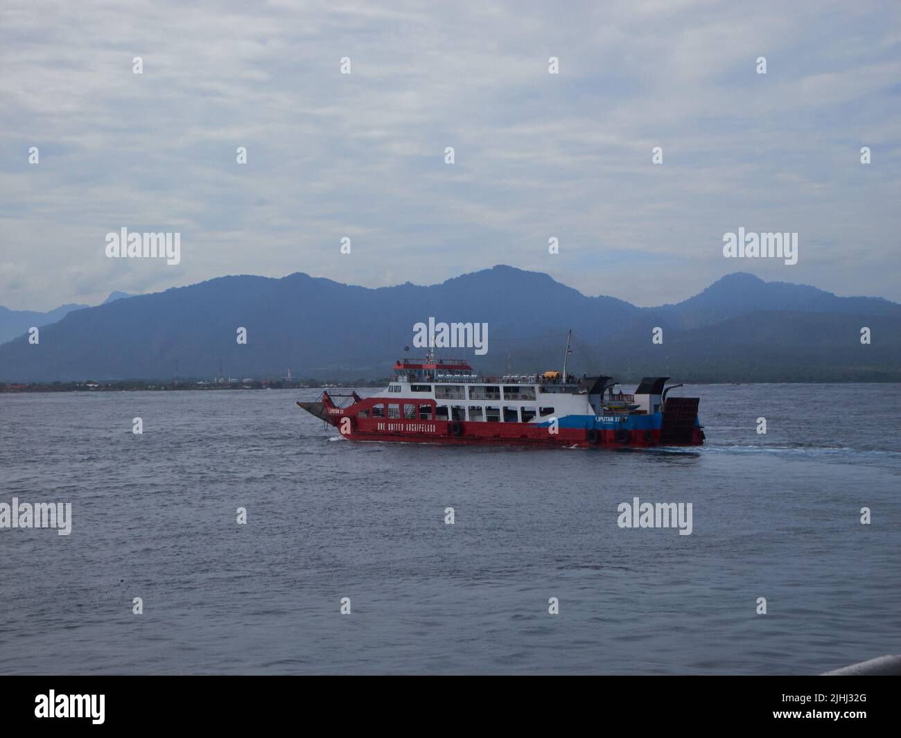 A passenger ferry rides in the waters of the Bali Strait, Indonesia ...