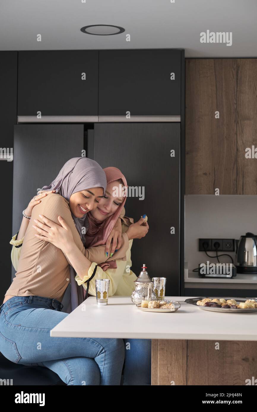 Two muslim friends hugging, drinking tea and eating arabic sweets Stock ...