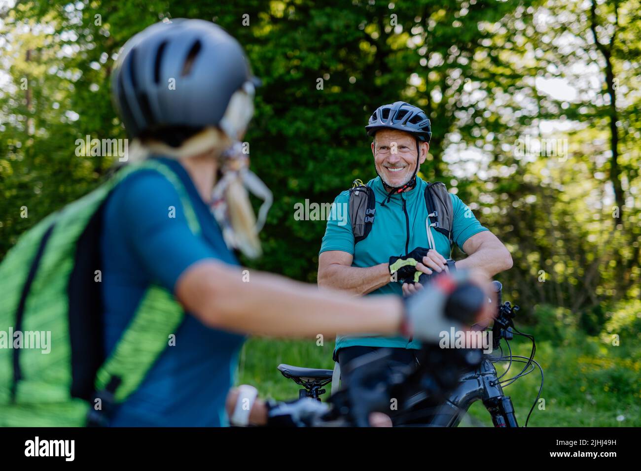 Portrait of active senior couple riding bicycles at summer park ...