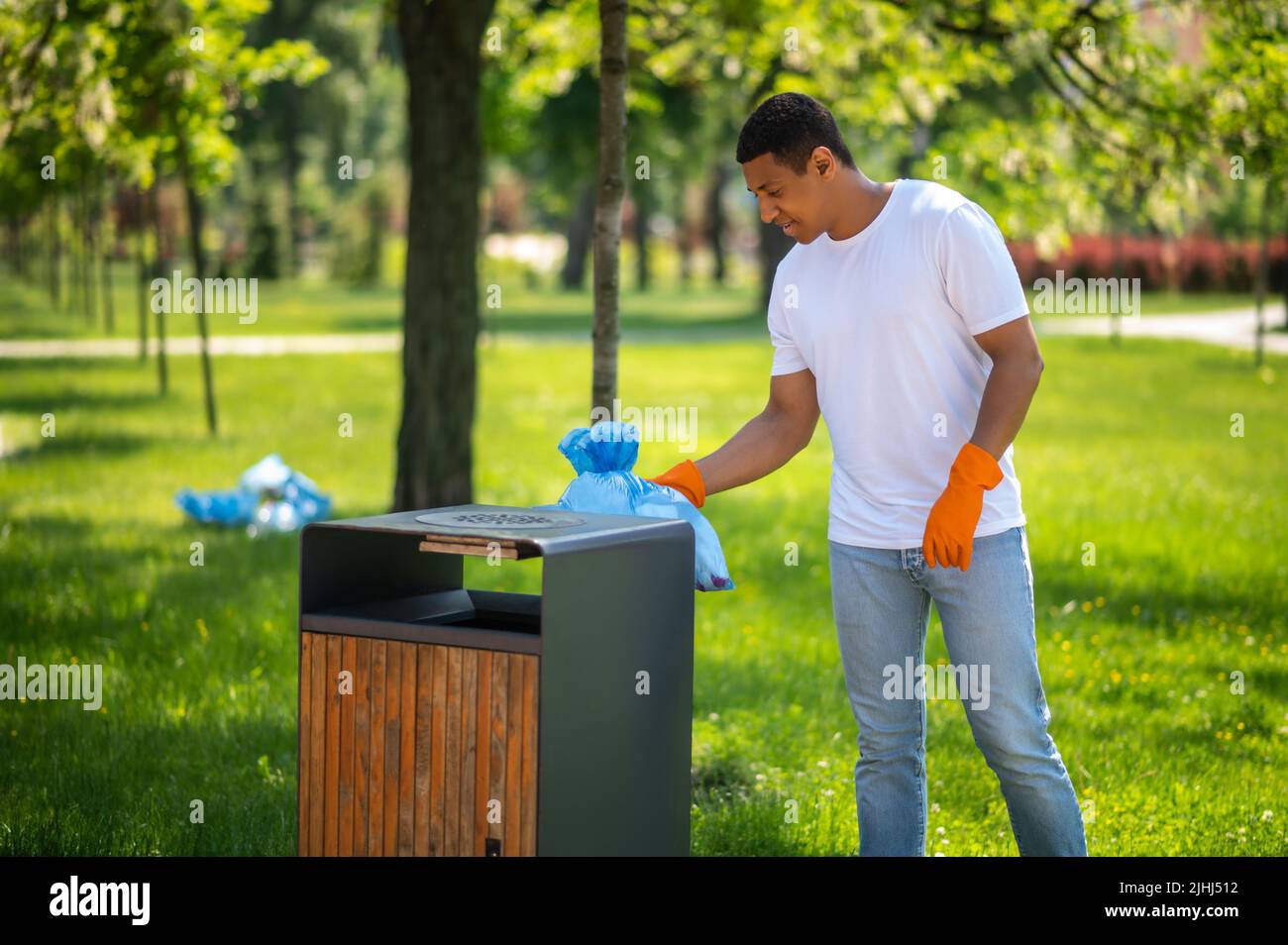 Guy with bag of waste standing near dumpster Stock Photo - Alamy