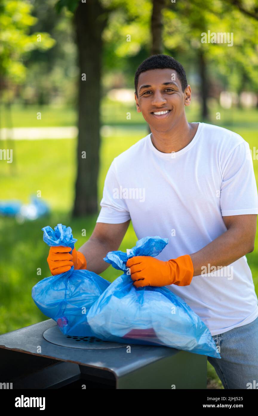 Guy smiling at camera holding waste bags Stock Photo - Alamy