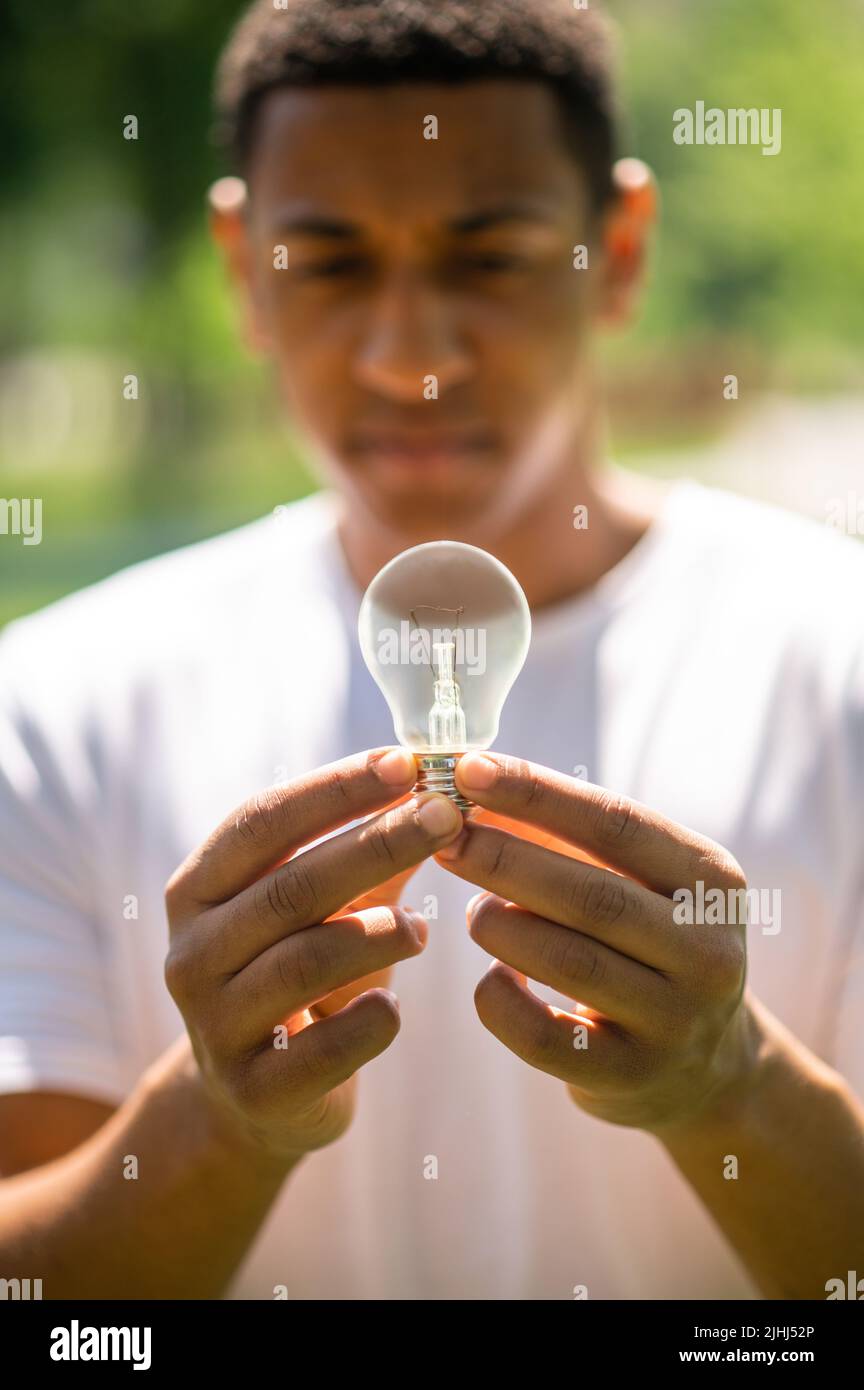 Guy looking at lightbulb in his hands Stock Photo - Alamy