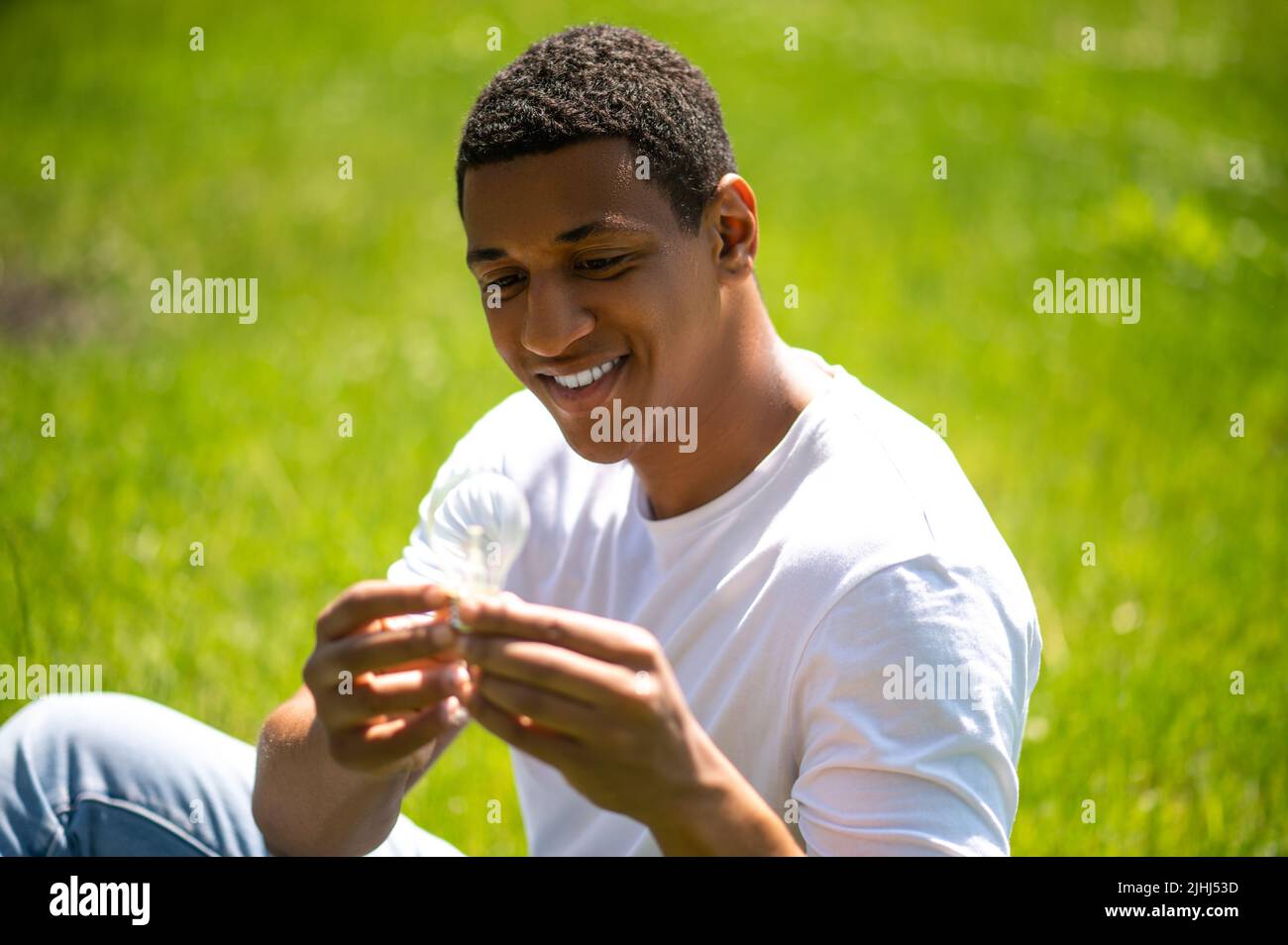 Man looking curiously at light bulb outdoors Stock Photo - Alamy