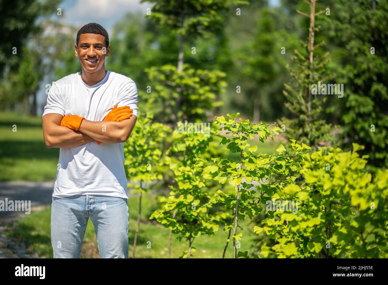 Guy smiling at camera standing near young trees Stock Photo - Alamy